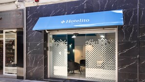Entrada de hotel com toldo azul identificado como 