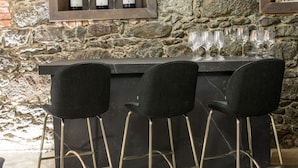 Uma área de bar com três banquetas pretas e bancada de mármore.
