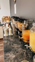 Uma mesa de pequeno-almoço com diversas opções de comida e bebidas.