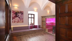 Quarto com um banco de madeira, parede de madeira com iluminação rosa e uma porta de madeira.