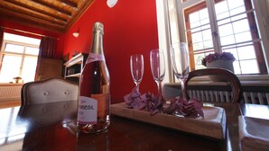 Uma mesa de madeira com uma garrafa de vinho rosé Chériex, duas taças de vinho vazias e um tabuleiro de madeira com flores.