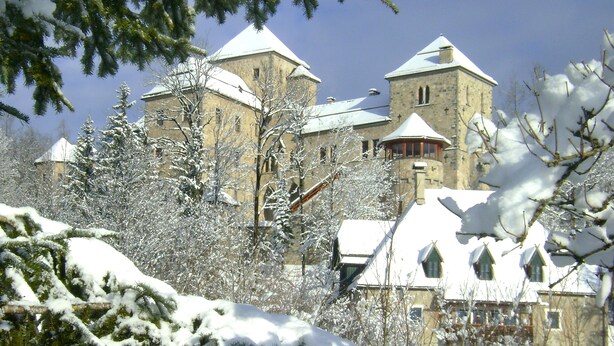 Um edifício histórico com várias torres e telhado coberto de neve.