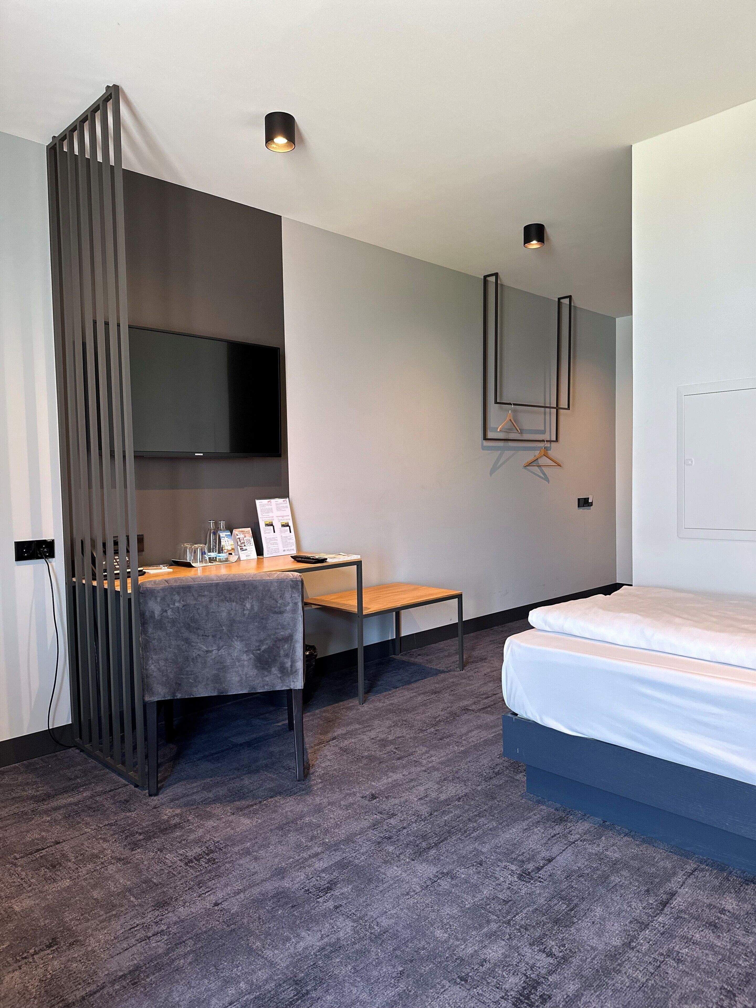 Quarto de hotel moderno com escrivaninha, cadeira e cama.
