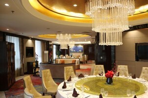 Uma sala de jantar formal com uma mesa redonda, cadeiras e um candelabro.