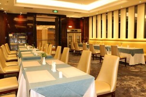 Uma sala de banquetes com longas mesas, cadeiras e piso coberto por carpete.