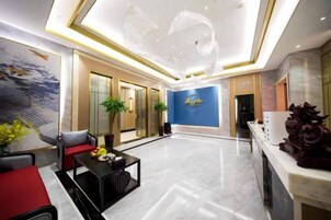 Um saguão de hotel com balcão de recepção, área de estar e um grande mural na parede.