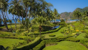 Um jardim exuberante com gramados bem cuidados, palmeiras e um espelho d'água.