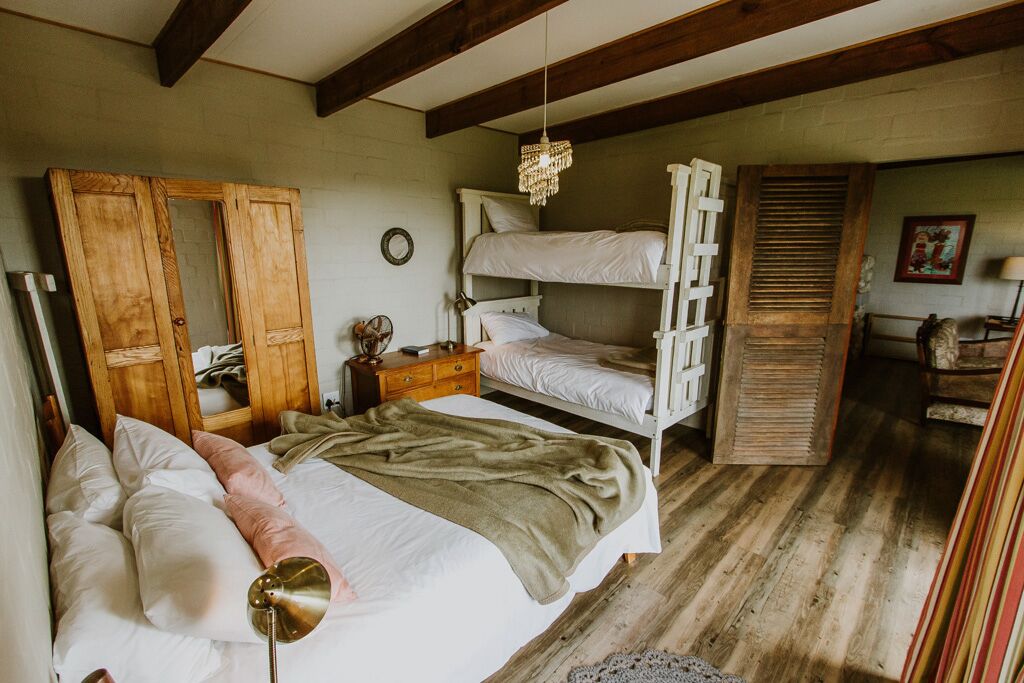 Um quarto rústico com uma cama beliche, um guarda-roupa de madeira, uma mesa de cabeceira e um candelabro.