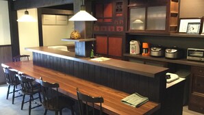 Uma área de bar com balcão de madeira, banquetas e uma máquina de café.