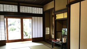 Um quarto japonês tradicional com tatames, portas corrediças e uma mesa baixa com uma chaleira.