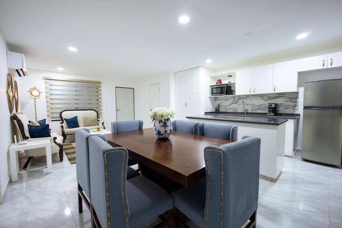 Cozinha moderna com armários brancos, painel de backsplash de mármore e eletrodomésticos de aço inoxidável.