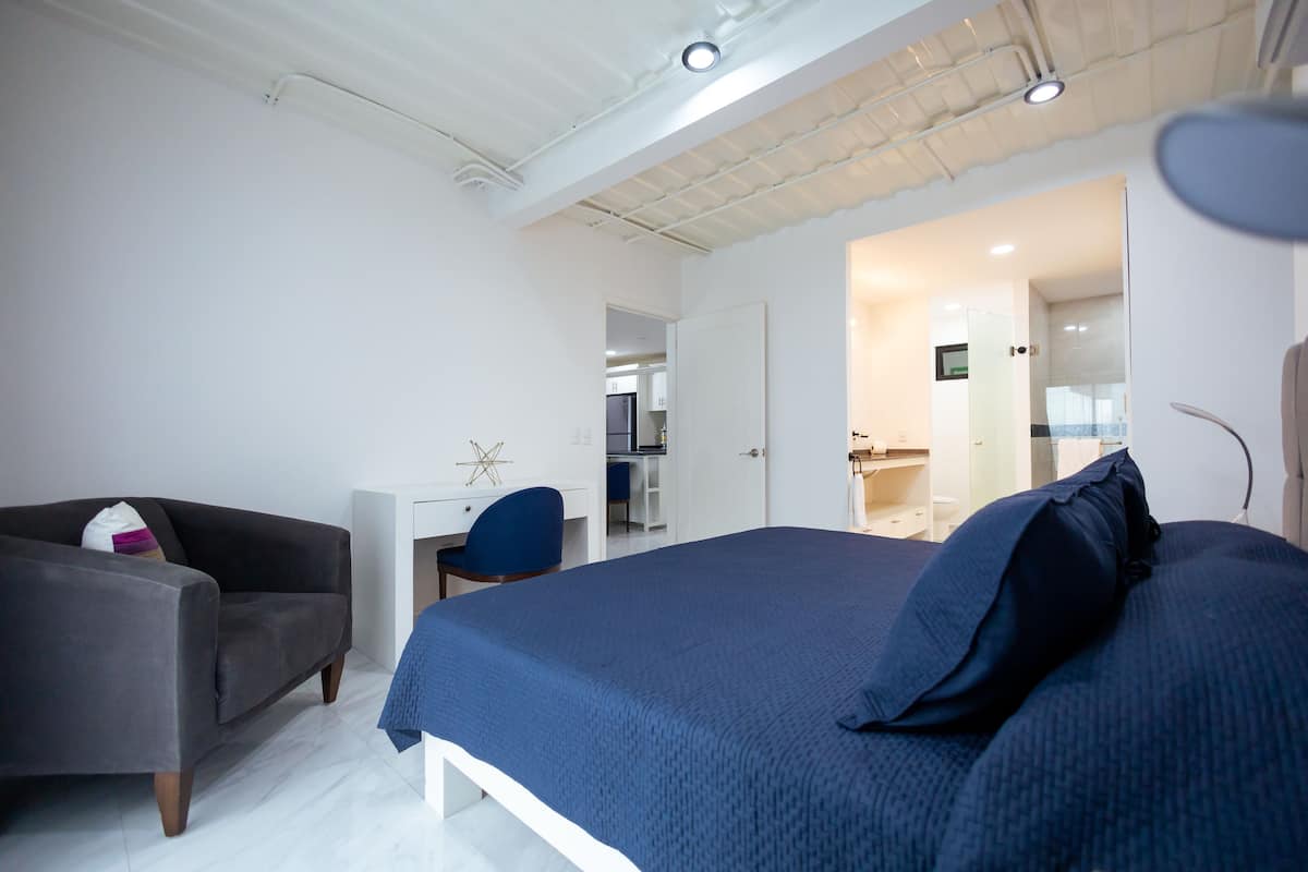 Quarto moderno com uma cama grande, uma escrivaninha e uma cadeira.