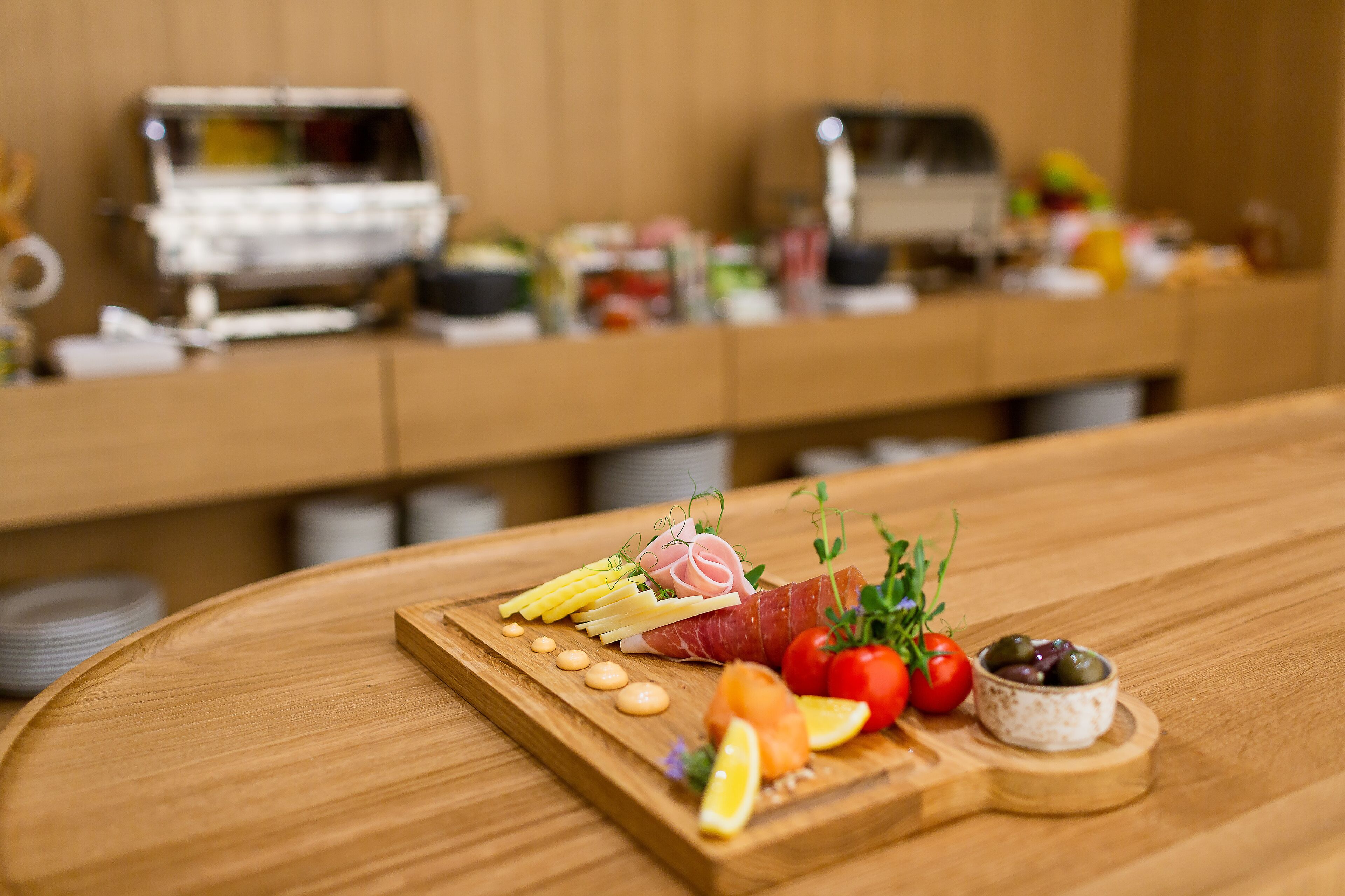 Uma mesa de madeira com diversos alimentos, incluindo queijo, tomate e azeitonas.