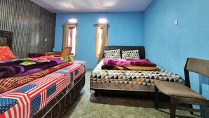 Quarto com duas camas, uma cadeira e uma janela com cortinas.