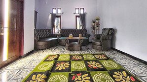 Uma sala de estar com tapete estampado, um sofá, uma mesa pequena e uma cadeira.