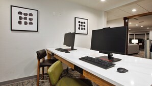 Um espaço de escritório moderno com escrivaninha branca, dois monitores, teclado, rato e cadeira verde.
