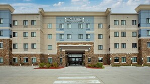 Um hotel Staybridge Suites com fachada moderna, vários andares e entrada central.