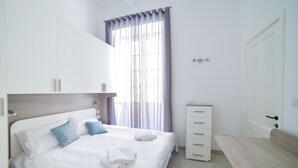 Quarto de hotel moderno com uma cama, escrivaninha e guarda-roupa.