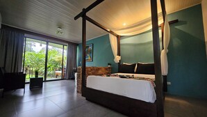 Uma cama com dossel, parede de pedra decorativa, grande janela com cortinas e vista para o verde lá fora.
