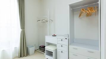 Quarto bem arrumado com um guarda-roupa branco, uma mesa de cabeceira e um cabideiro.