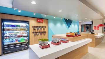 Um espaço comercial moderno com máquina de venda automática, exposição de lanches e uma mesa de recepção.