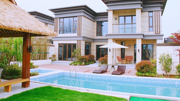 Uma casa moderna com piscina, espreguiçadeiras e uma cobertura de colmo.