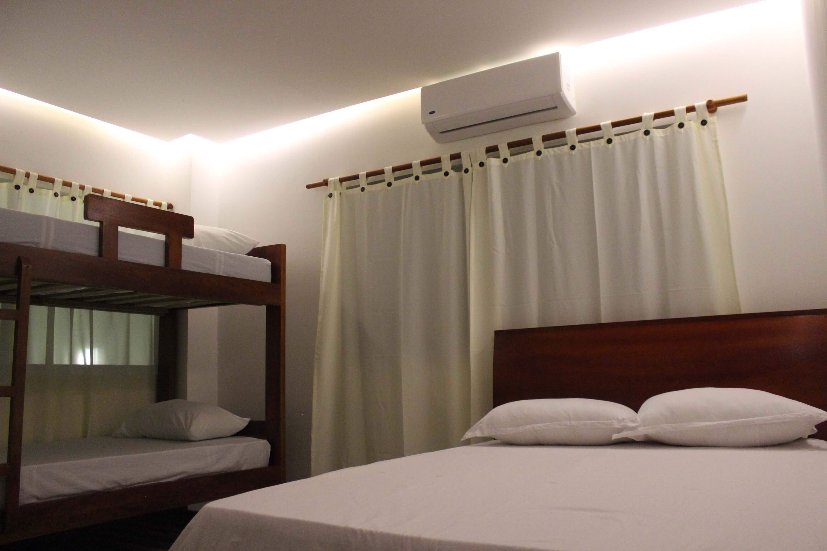 Um quarto com uma cama beliche, uma cama de solteiro e uma cortina.