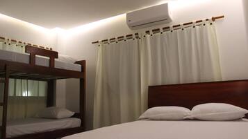 Um quarto com uma cama beliche, uma cama de solteiro e uma cortina.
