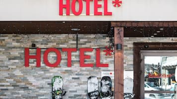 Placa de hotel com a inscrição 'SKI-INN RECEPTION HOTEL' e snowboards encostados na parede.