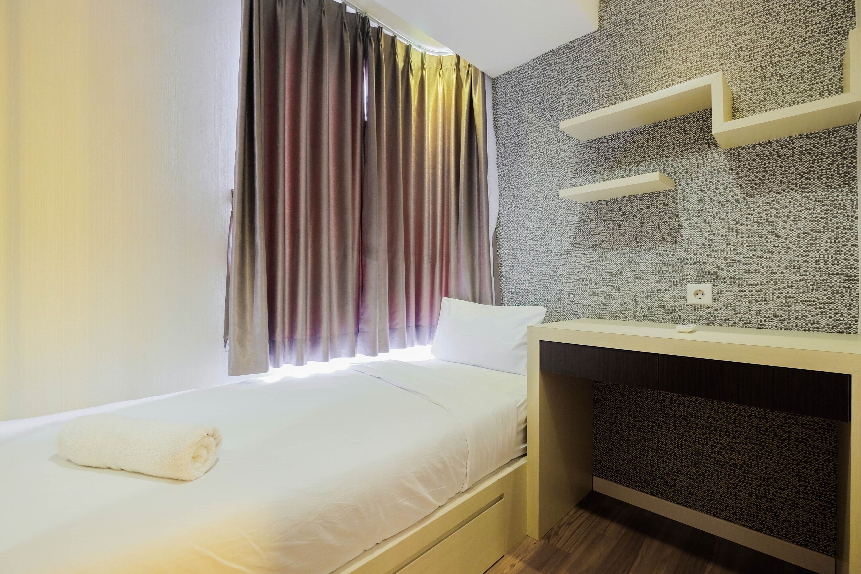 Quarto de hotel com cama, escrivaninha e parede com padrão texturizado.