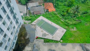 Vista aérea de uma área residencial com um edifício grande, um pequeno pátio com área verde e uma bandeira vermelha.