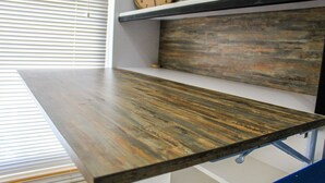 Uma mesa de madeira com um relógio numa estante acima.