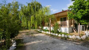 Uma casa com varanda, cercada por árvores e um caminho de cascalho.