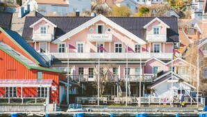 Um edifício rosa com varanda e bandeiras, com a inscrição "Victoria Hotel".