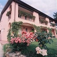 Um edifício rosa com varanda e jardim cheio de flores cor-de-rosa.