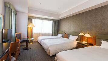 Quarto de hotel com duas camas, uma escrivaninha, uma cadeira, um abajur e uma televisão.