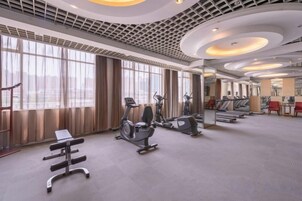 Academia com equipamentos de ginástica, janelas amplas e design moderno no teto.