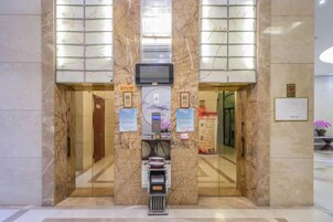 Um hall de entrada com um pilar de mármore, um quiosque de informações digitais e uma mesa de recepção.