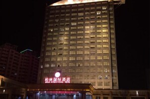Um prédio alto de hotel com sinalização iluminada no topo.