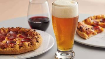 Pizza com pepperoni e um copo de cerveja sobre uma mesa.