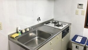 Uma cafeteira/bule, um frigorífico, uma placa de cozinha 