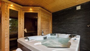 Uma cabana de madeira com hidromassagem, paredes de madeira e uma parede de pedra preta.