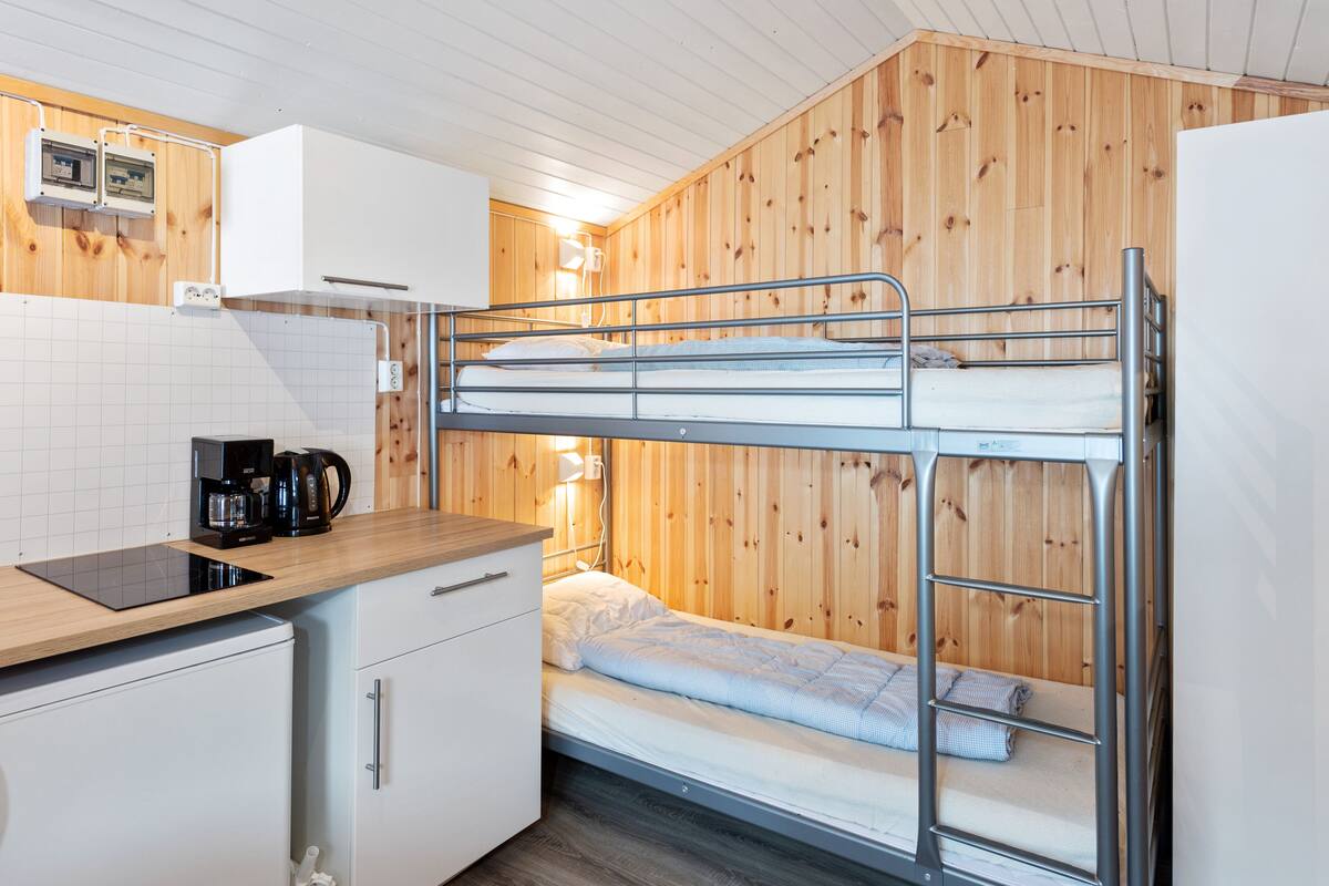Quarto com beliche e cozinha compacta, incluindo cafeteira e pequena geladeira.