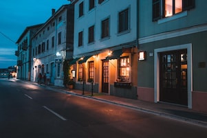 Vista da rua de um edifício com restaurante no andar térreo, com uma fileira de janelas com toldos e entrada visível.