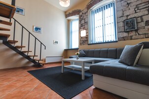 Uma sala de estar moderna com escada, um sofá cinza, uma mesa de centro branca e um tapete preto.