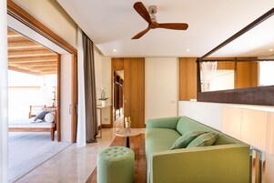 Uma sala de estar moderna com um sofá verde, uma mesa de centro redonda e um ventilador de teto.