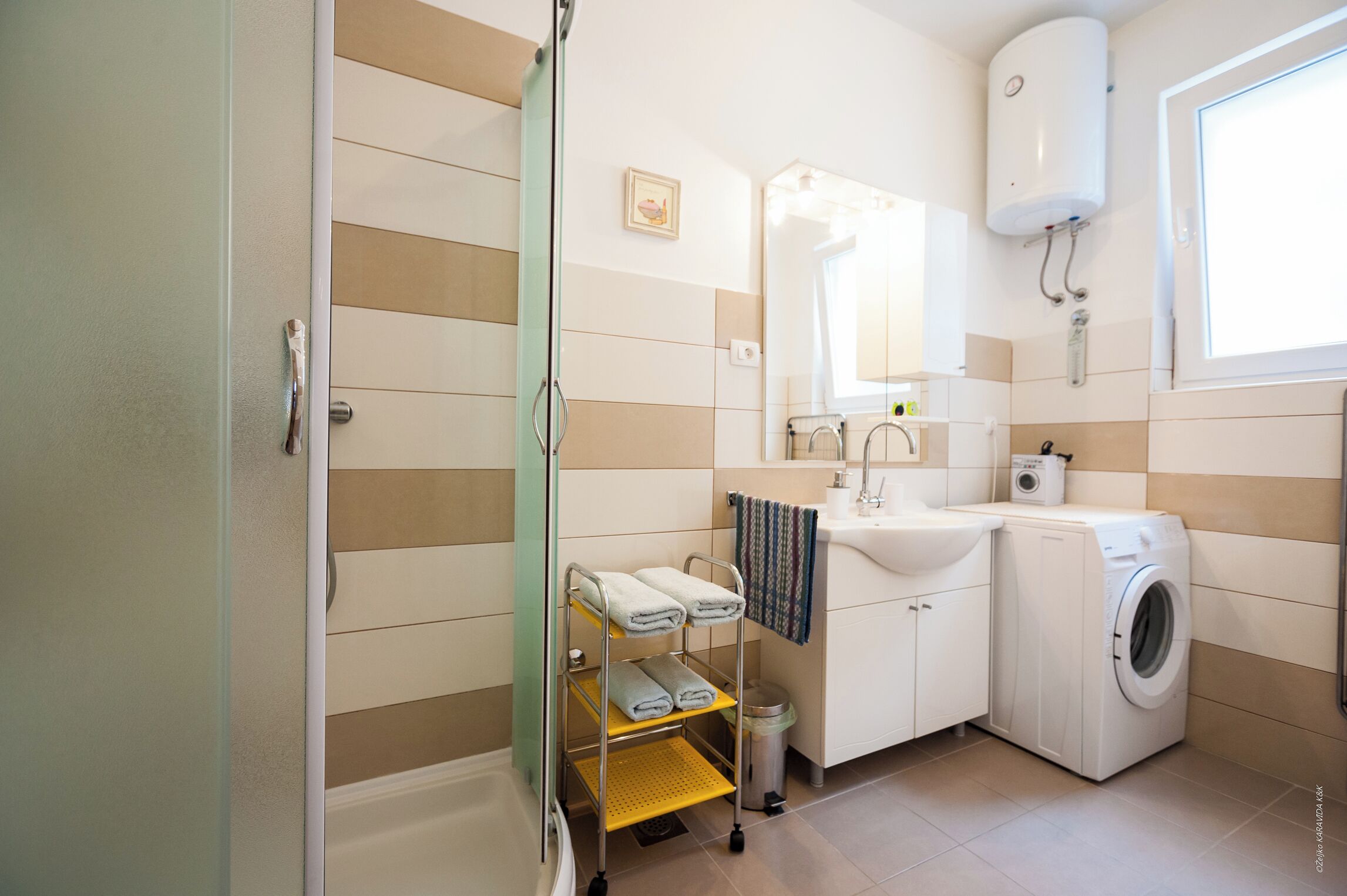 Casa de banho compacta com chuveiro, pia, máquina de lavar roupa e sanita.