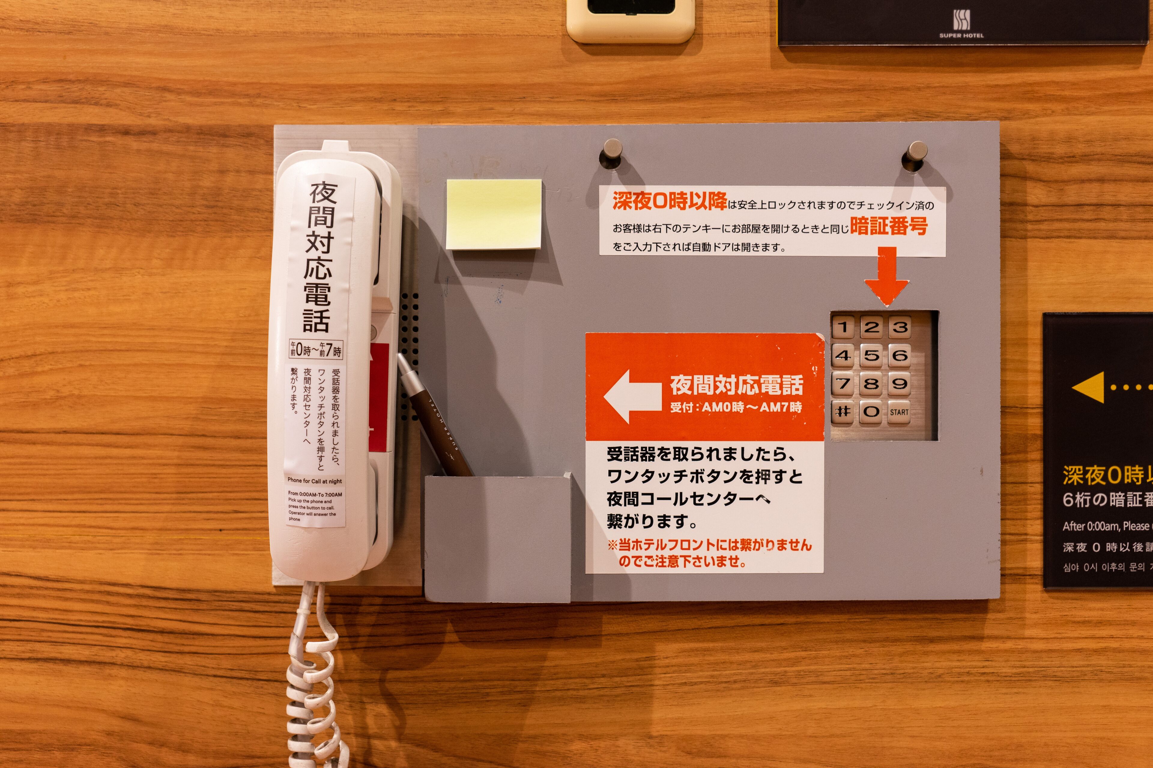 Telefone e interfone de um quarto de hotel, com instruções em japonês.