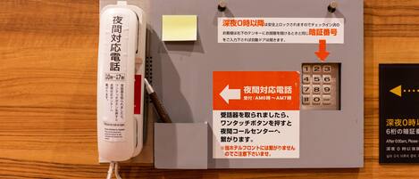 Telefone e interfone de um quarto de hotel, com instruções em japonês.