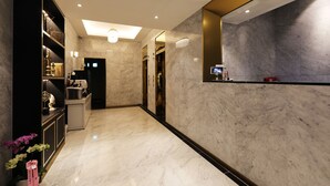 Um hall de hotel moderno com piso de mármore, um balcão de recepção e um espelho grande.